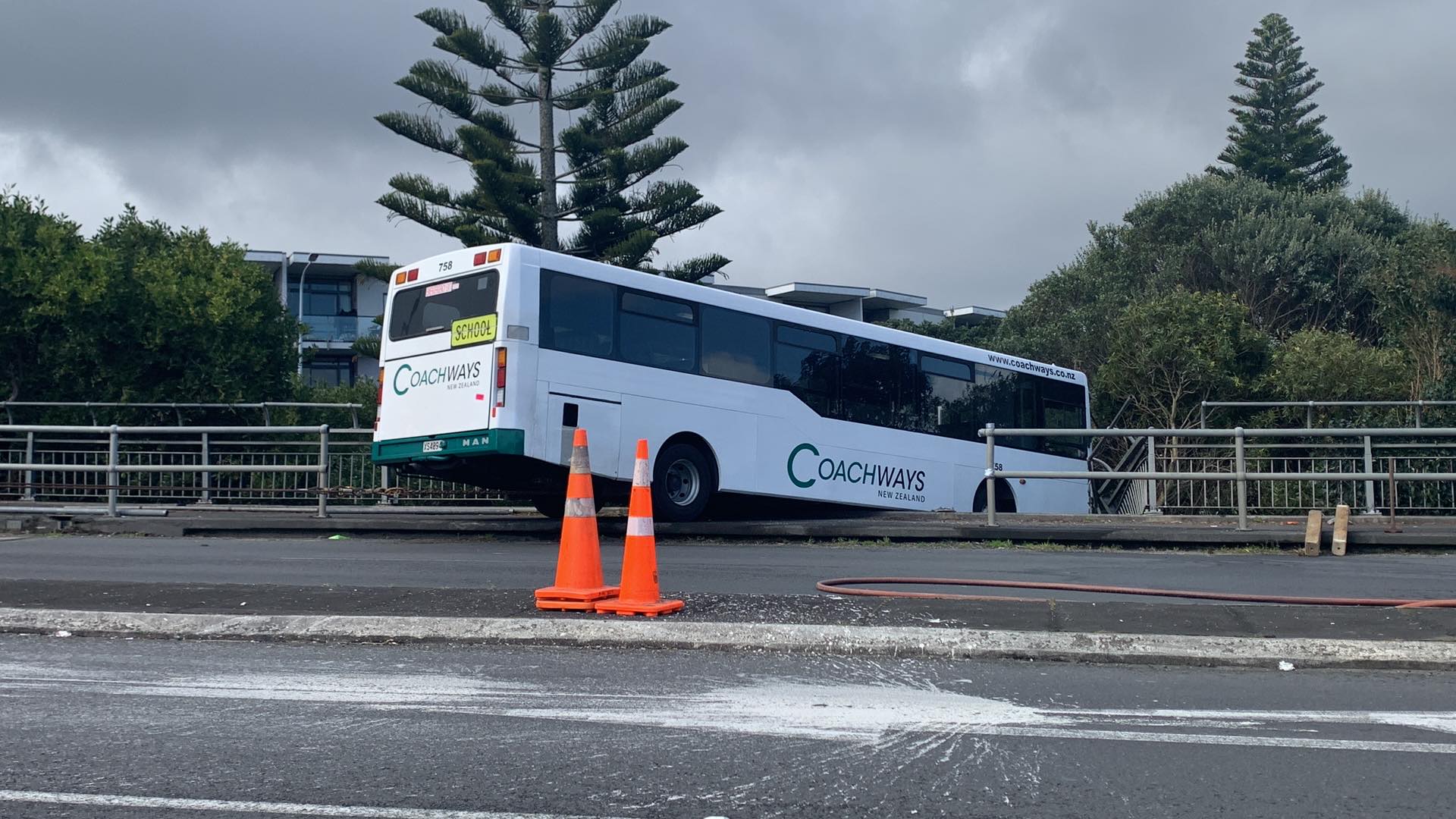 Front of school bus hangs off overpass after Auckland crash